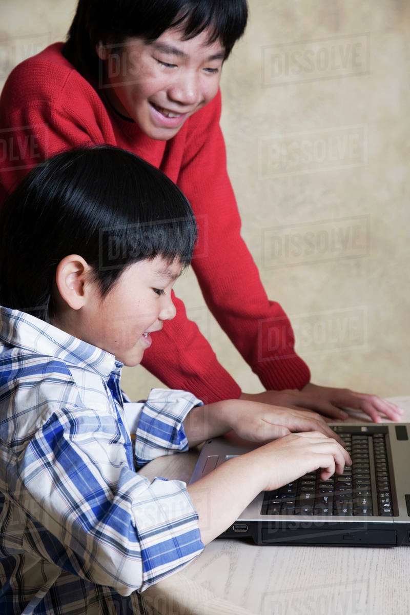 Asian brothers looking at laptop - Royalty-free Stock Photo | Dissolve
