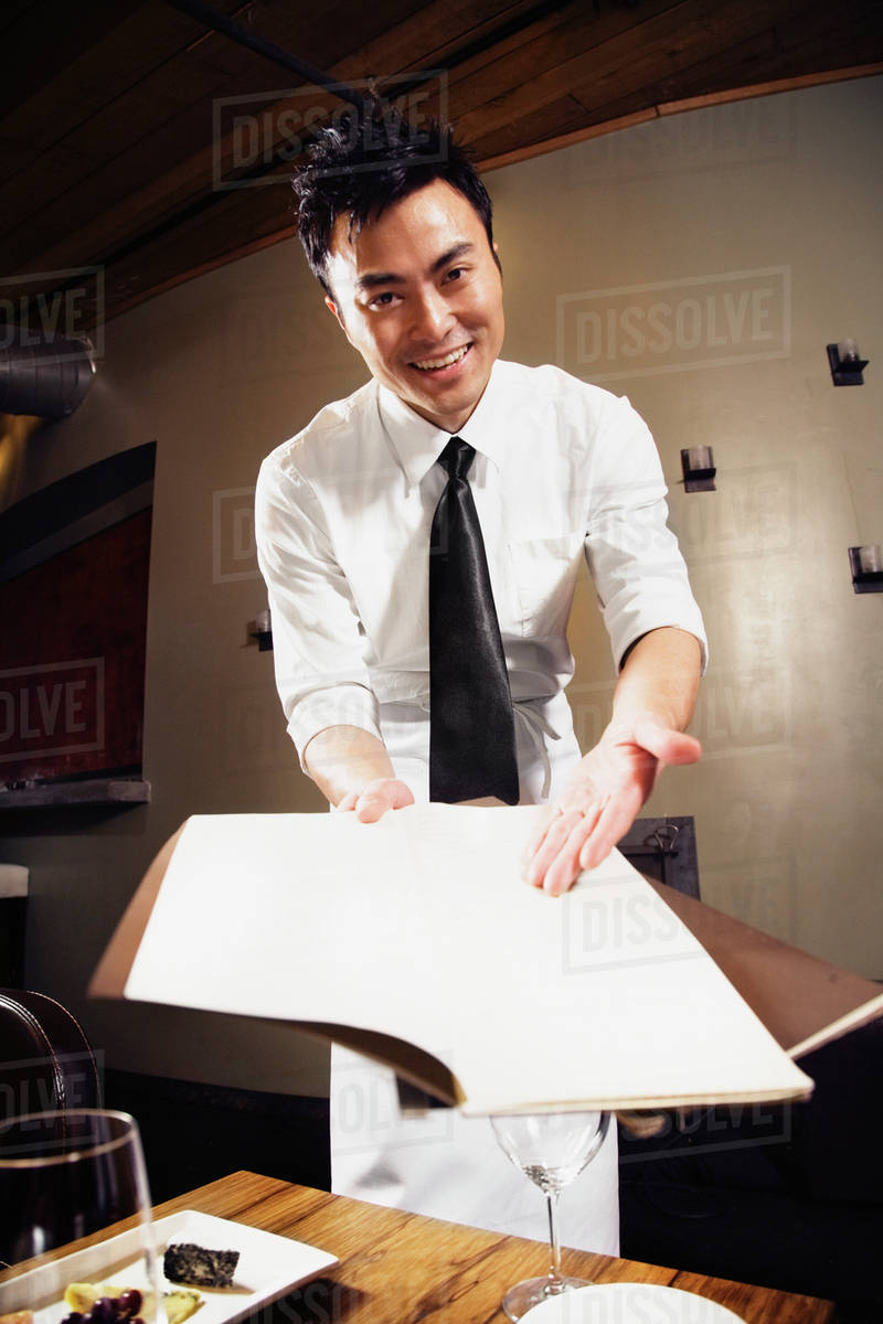 Asian waiter pointing to menu - Stock Photo - Dissolve