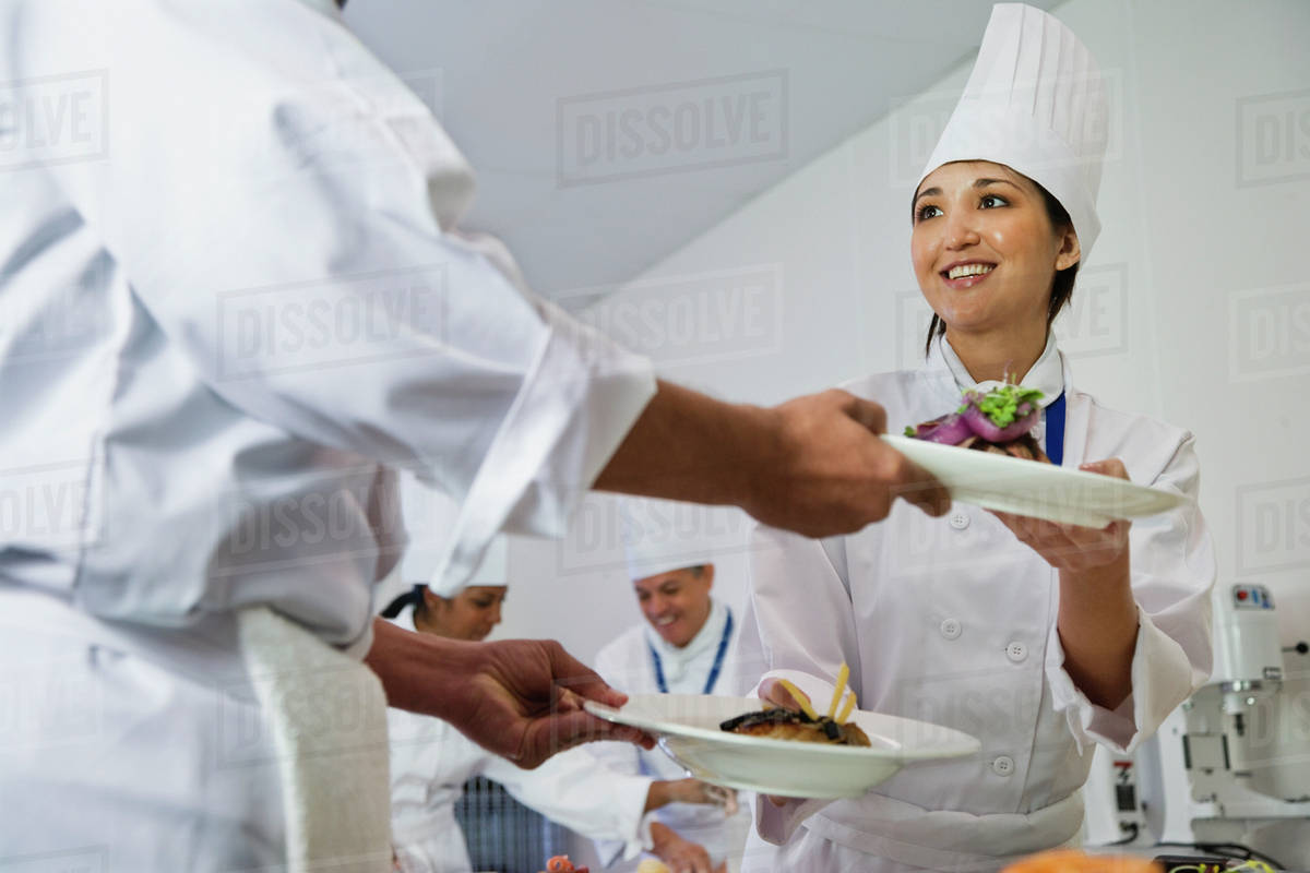 Multi-ethnic chefs carrying plates of food - Stock Photo - Dissolve