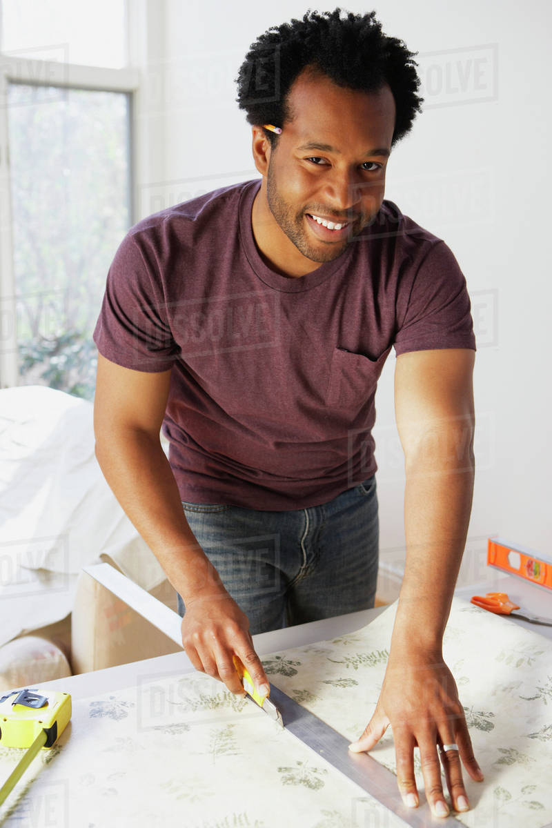 African man measuring wallpaper - Stock Photo - Dissolve