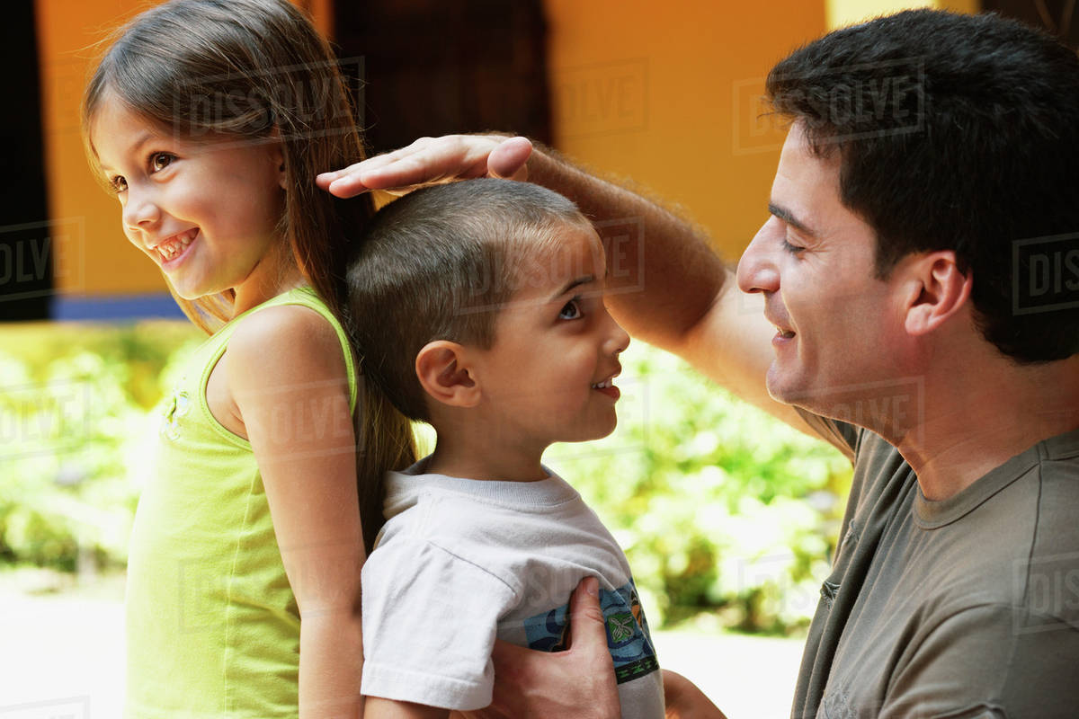 Father comparing children's height - Royalty-free Stock Photo | Dissolve