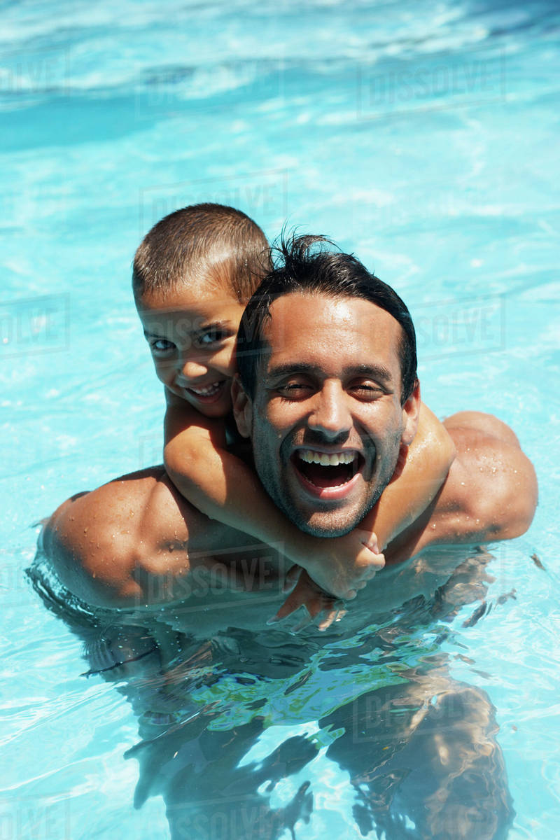 Father giving son piggyback ride in swimming pool - Stock Photo - Dissolve