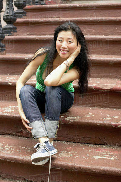 Asian woman sitting on front steps - Stock Photo - Dissolve