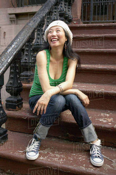 Asian woman sitting on front steps - Royalty-free Stock Photo | Dissolve