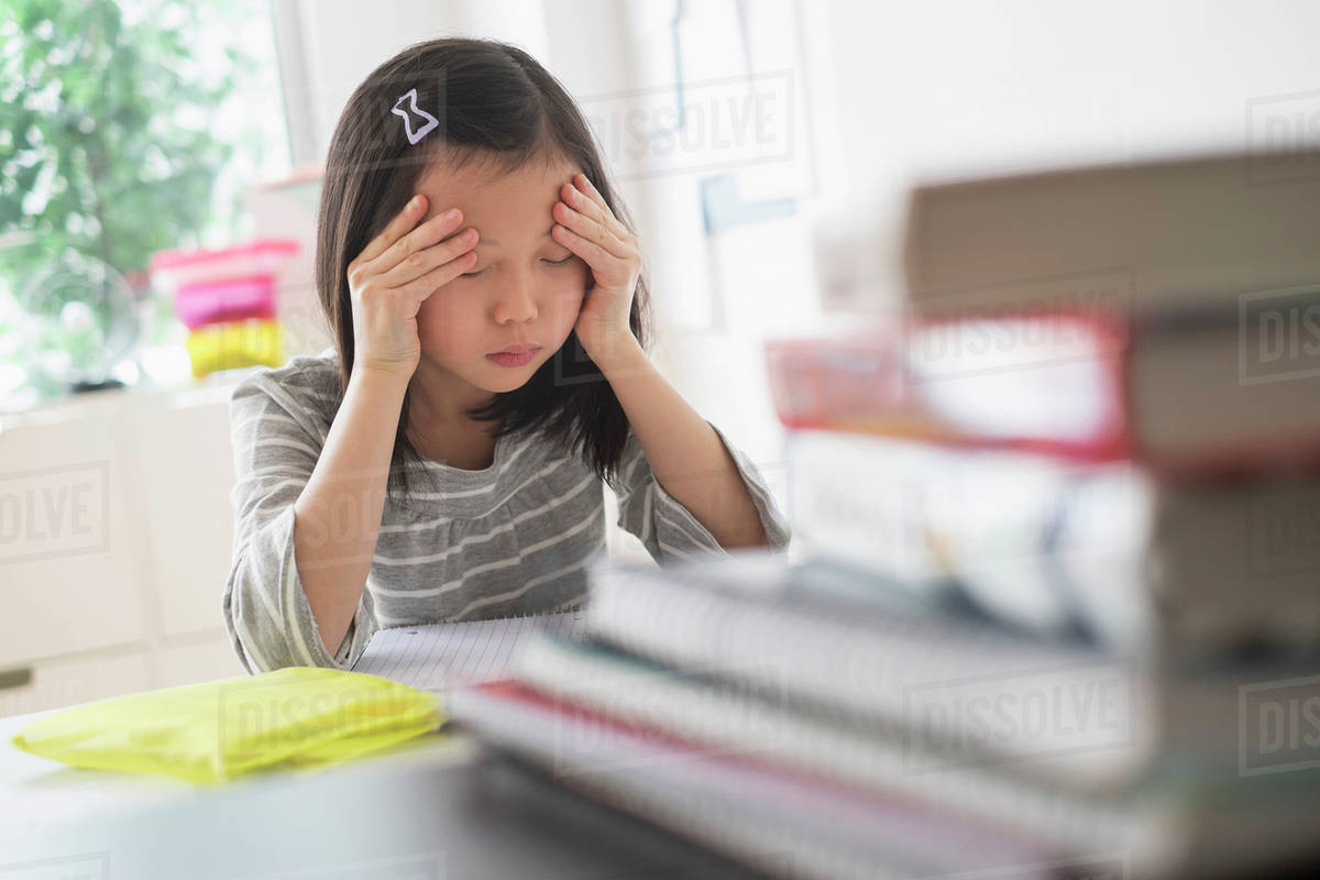 Anxious Chinese student rubbing forehead doing homework - Royalty-free ...