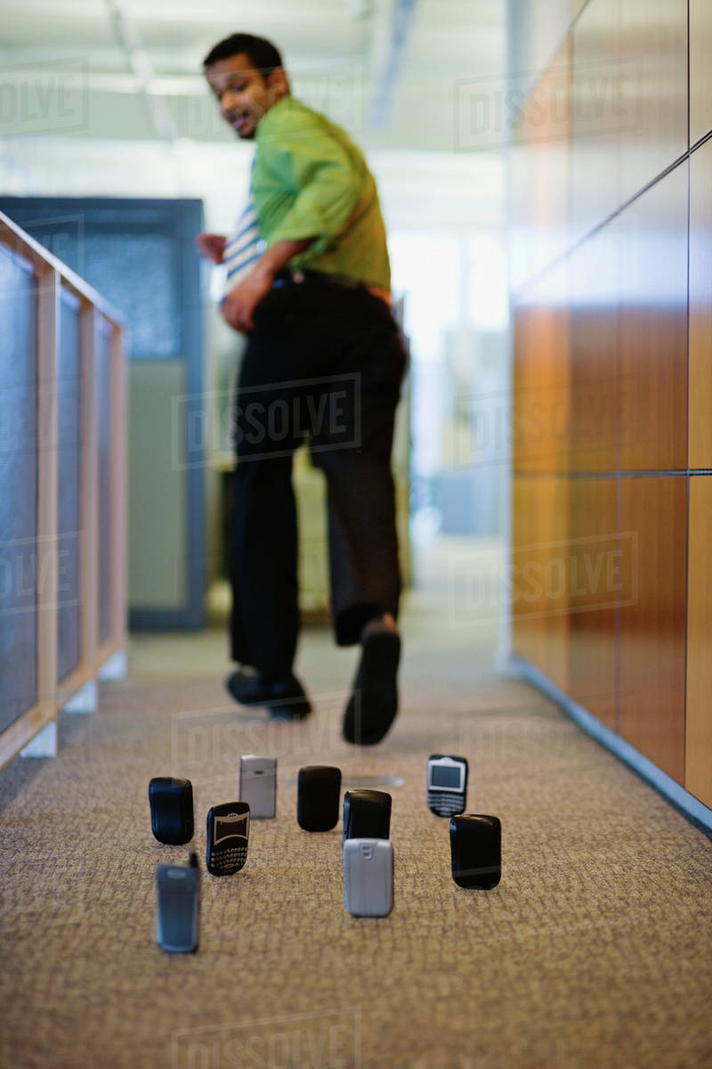 Indian businessman running from cell phones on office floor - Royalty ...