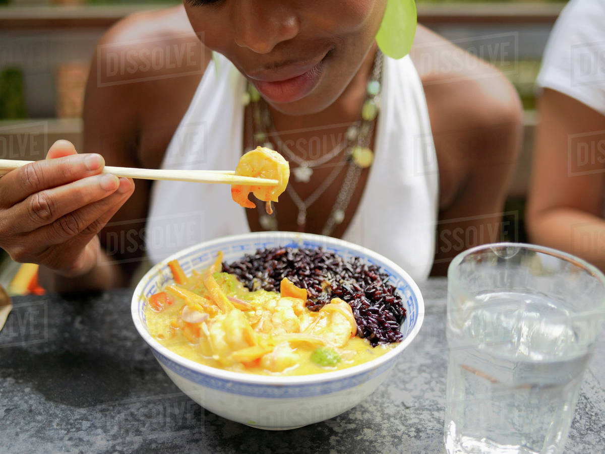 African woman eating Asian food in restaurant - Stock Photo - Dissolve
