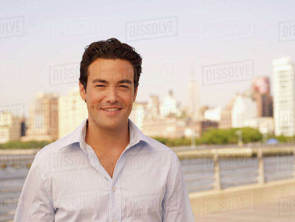 Man standing at waterfront with cityscape in background - Stock Photo ...