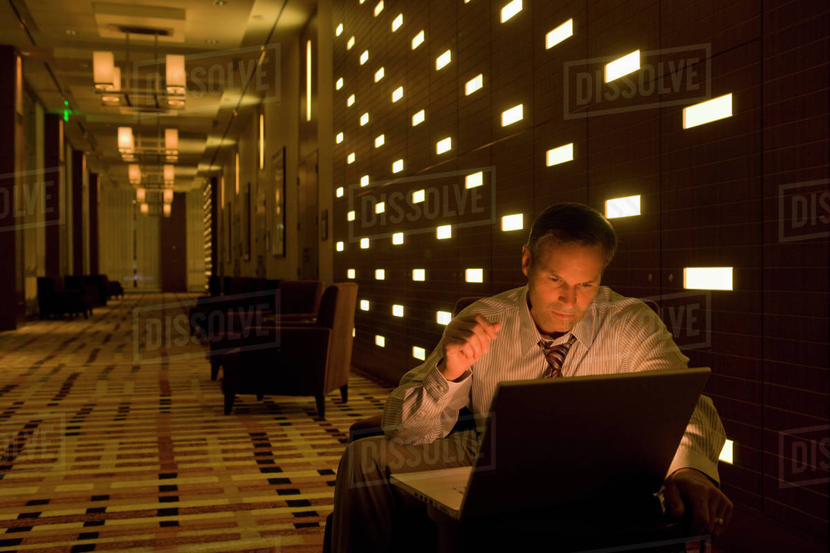 Businessman working on laptop late in lobby - Royalty-free Stock Photo ...