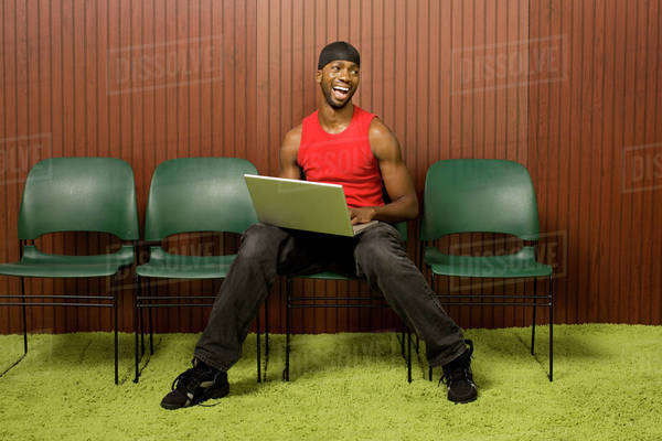 African man using laptop and laughing - Stock Photo - Dissolve