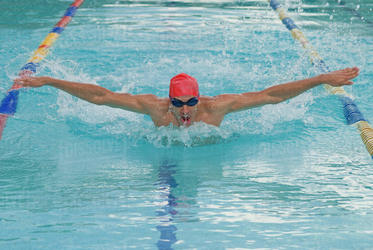 Hispanic man swimming in swimming pool - Stock Photo - Dissolve