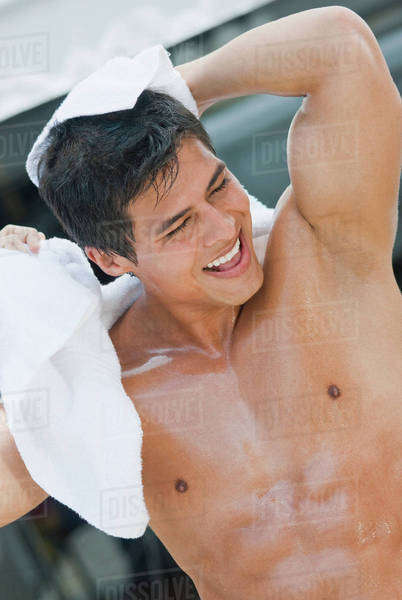 Wet Hispanic man drying off - Stock Photo - Dissolve