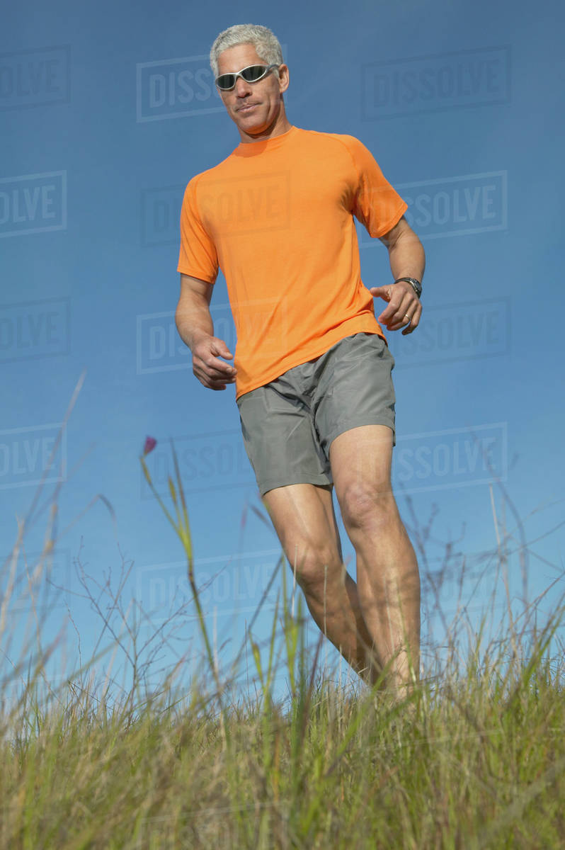 Middle-aged man walking through grass - Royalty-free Stock Photo | Dissolve