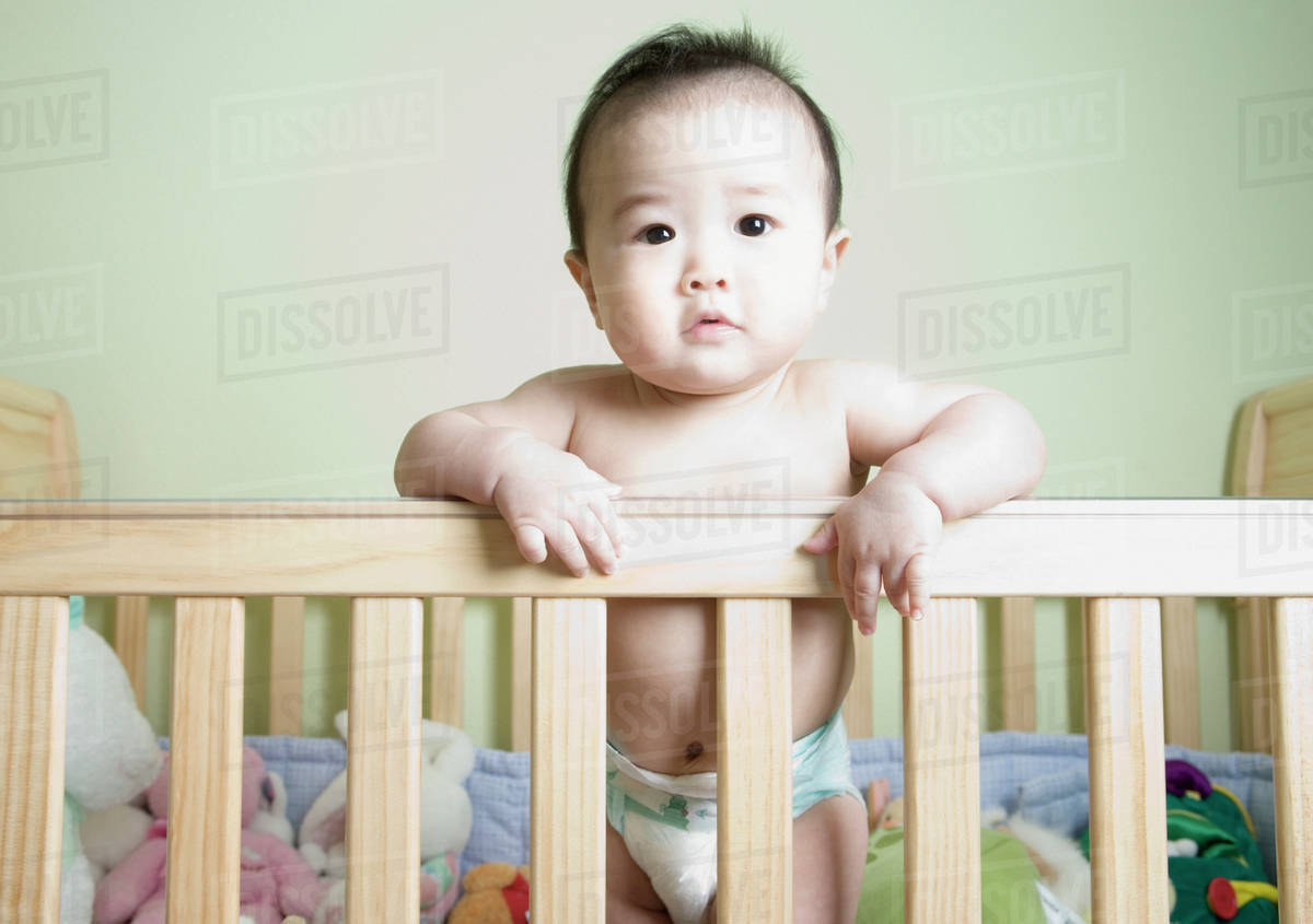 Asian baby standing in crib - Royalty-free Stock Photo | Dissolve