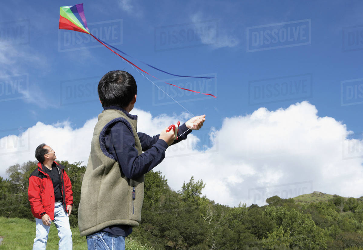 Asian father and son flying a kite - Royalty-free Stock Photo | Dissolve