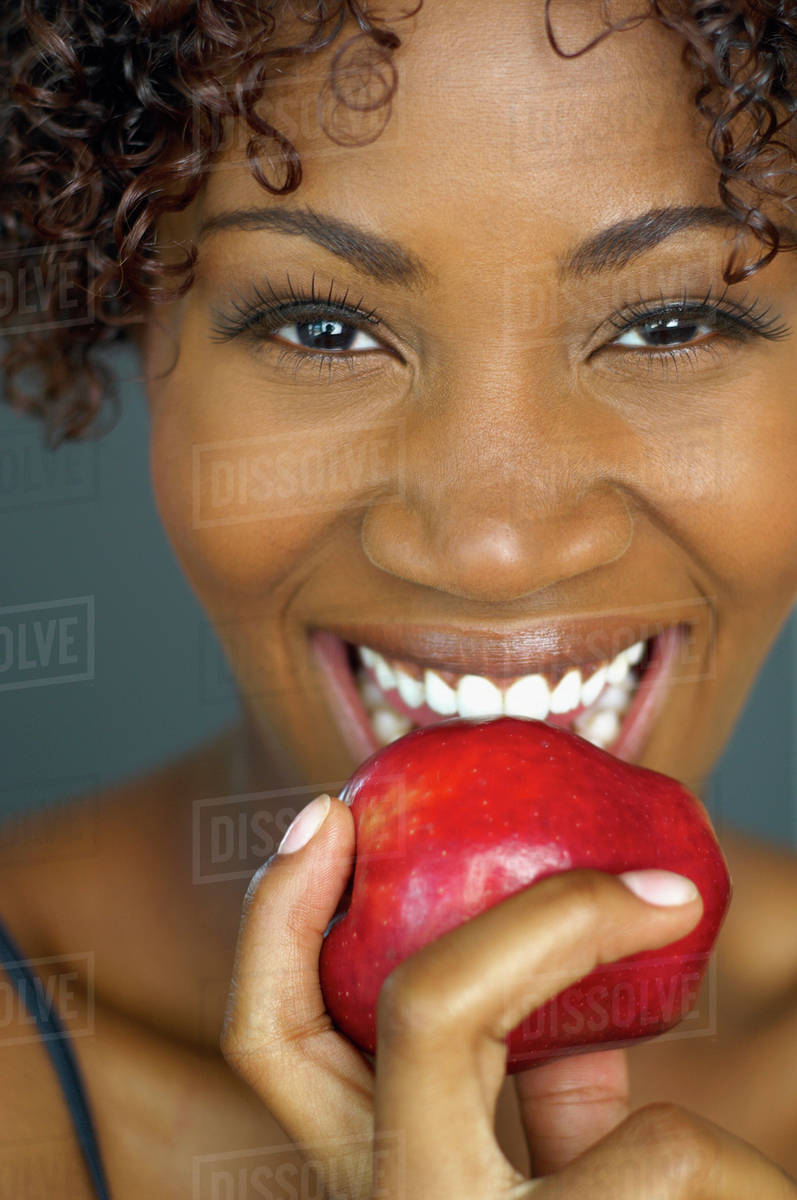 Close up of African woman eating apple - Stock Photo - Dissolve
