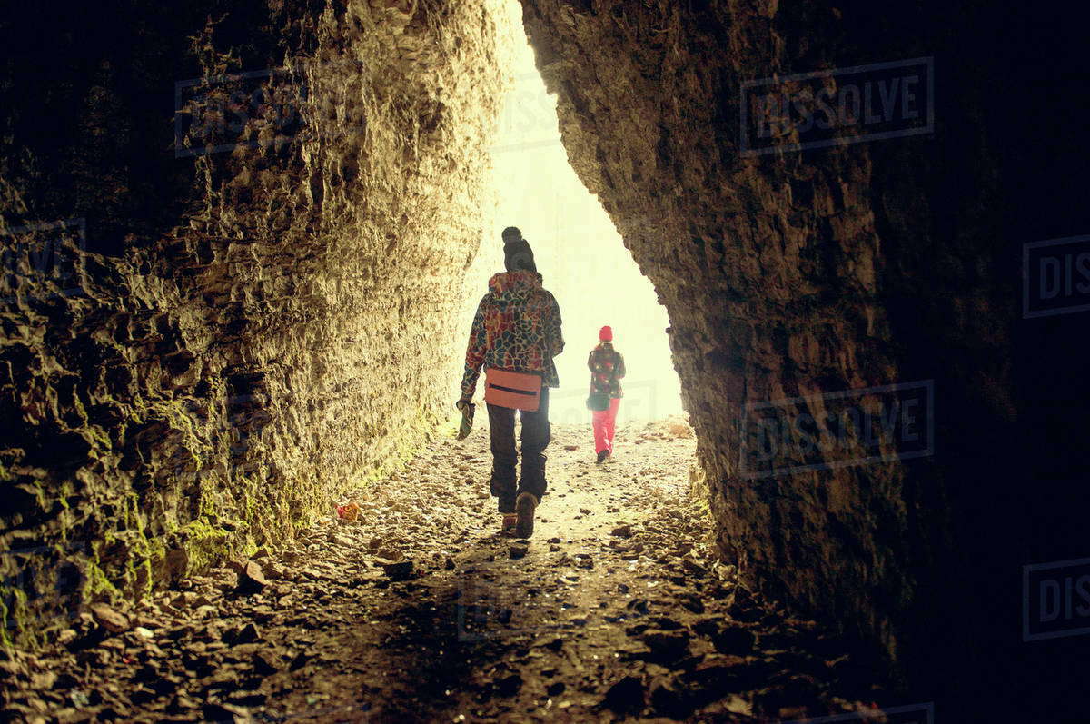 Caucasian hikers walking in rocky cave - Royalty-free Stock Photo ...