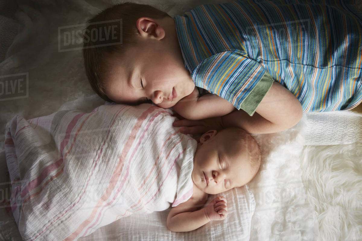 Boy napping with newborn sibling on bed - Royalty-free Stock Photo ...