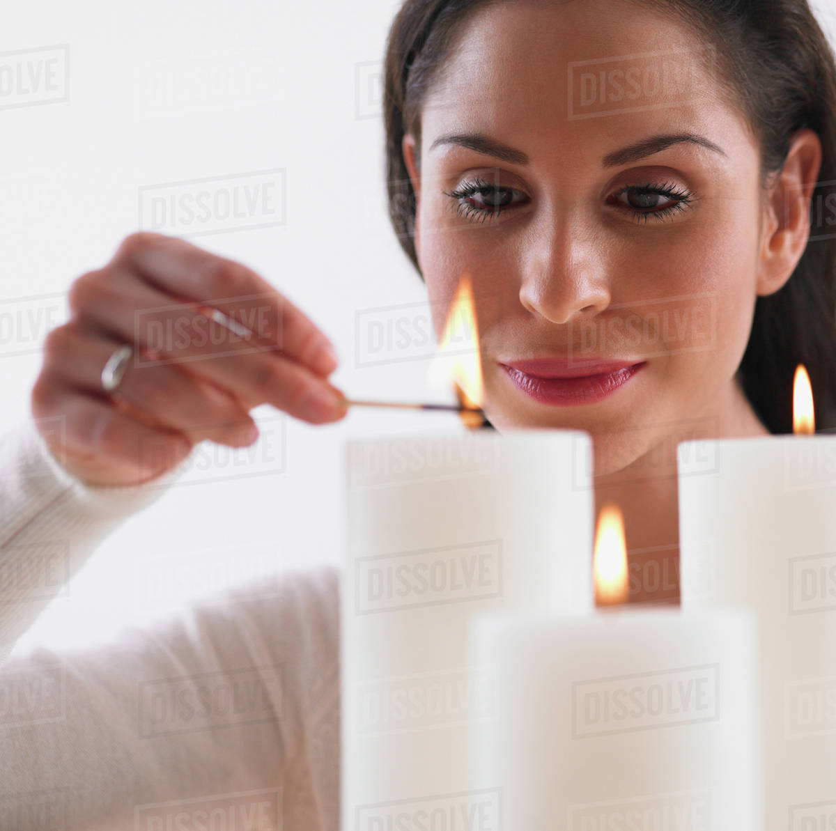 Close up of Hispanic woman lighting candles - Stock Photo - Dissolve