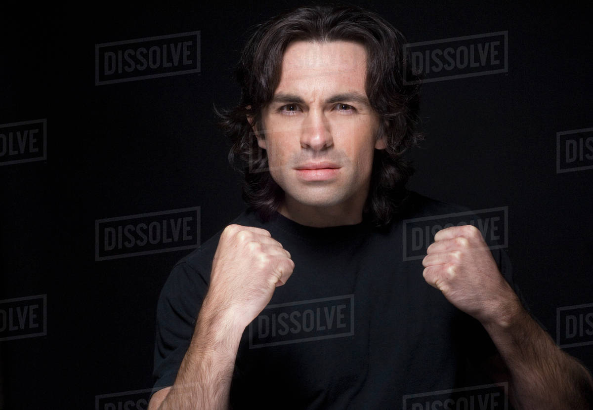 Portrait of man holding fists up - Stock Photo - Dissolve