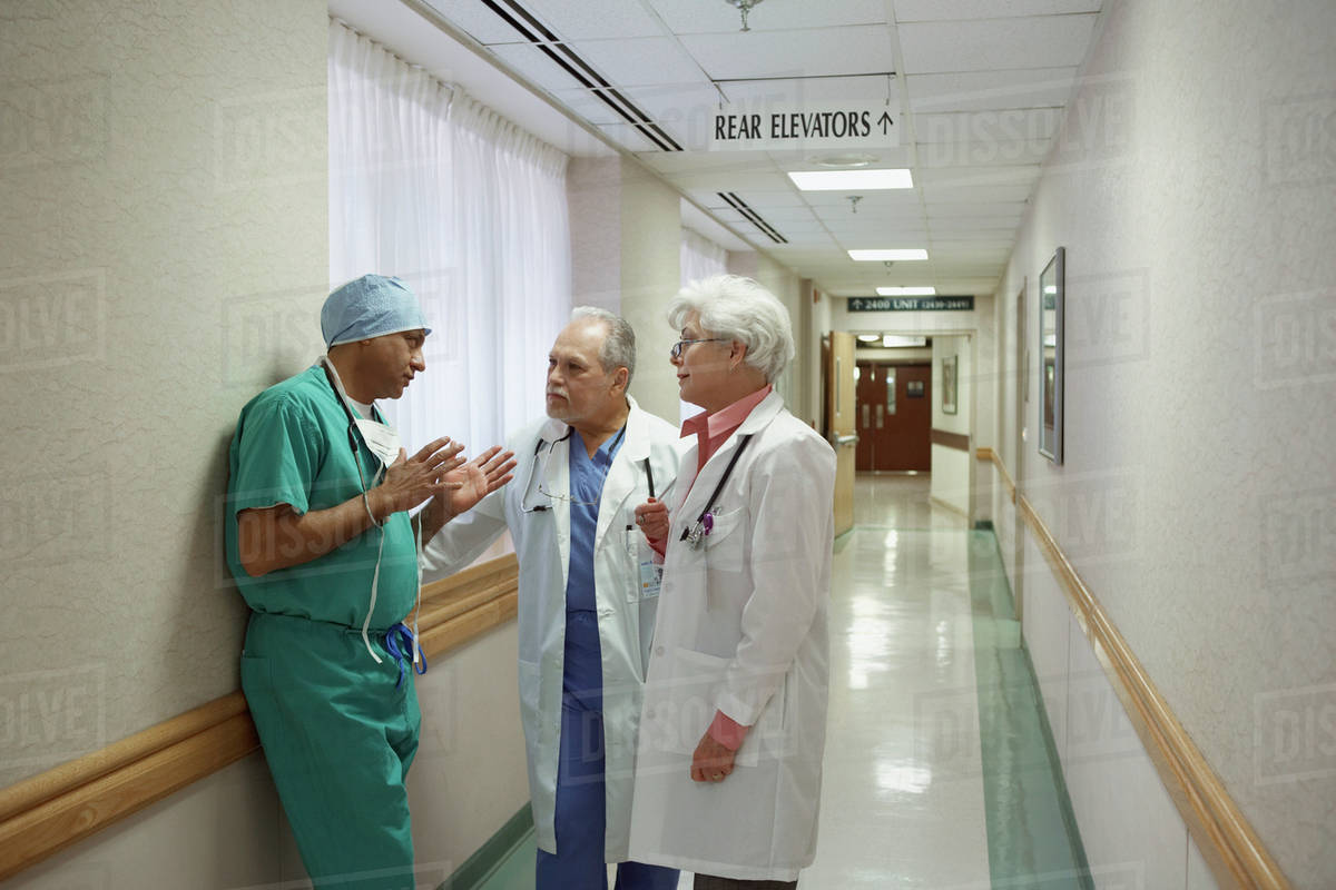 Surgeon talking to two doctors in hospital hallway - Royalty-free Stock ...