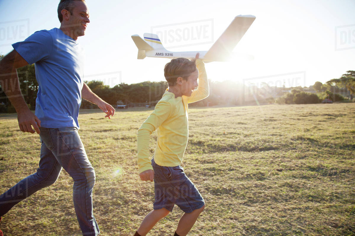 Caucasian father and son flying model airplane in field - Royalty-free ...