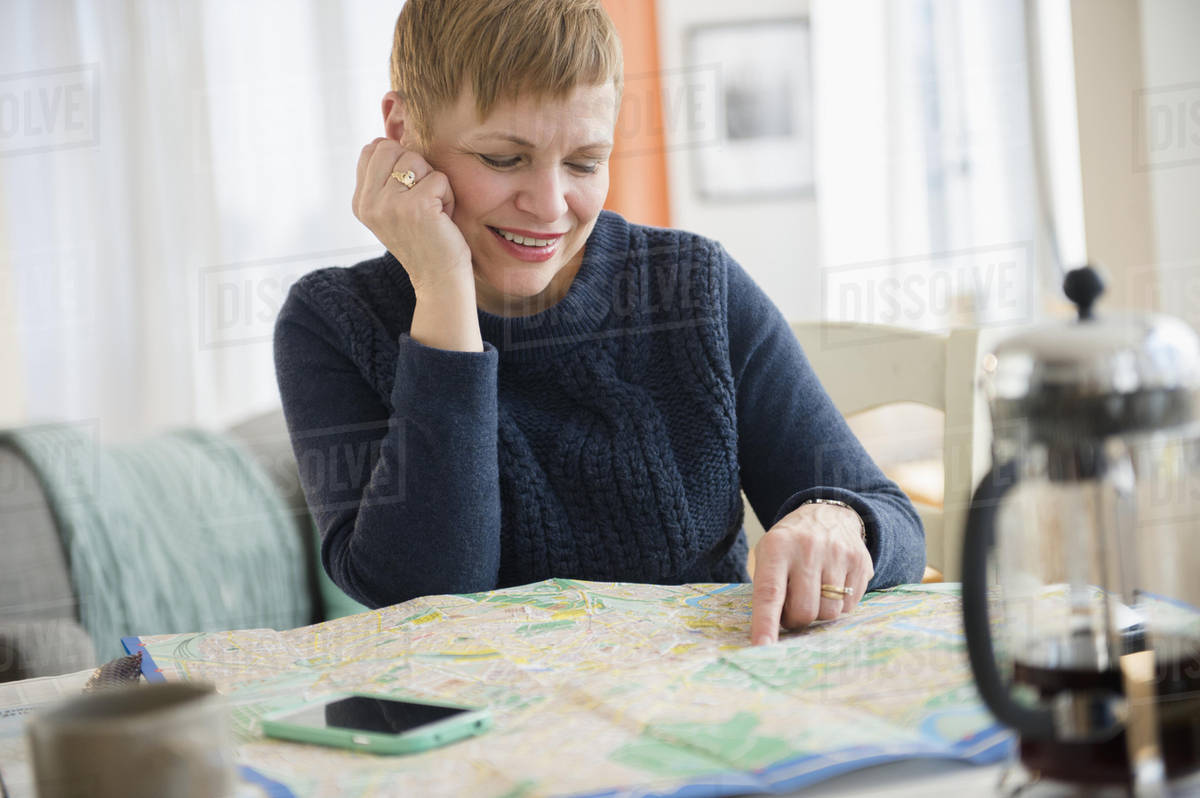 Caucasian woman reading map at table - Royalty-free Stock Photo | Dissolve