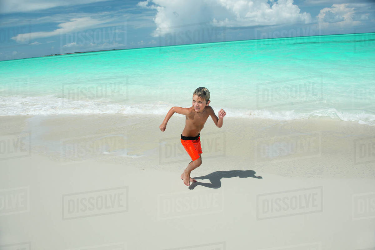 Hispanic boy running on beach - Royalty-free Stock Photo | Dissolve