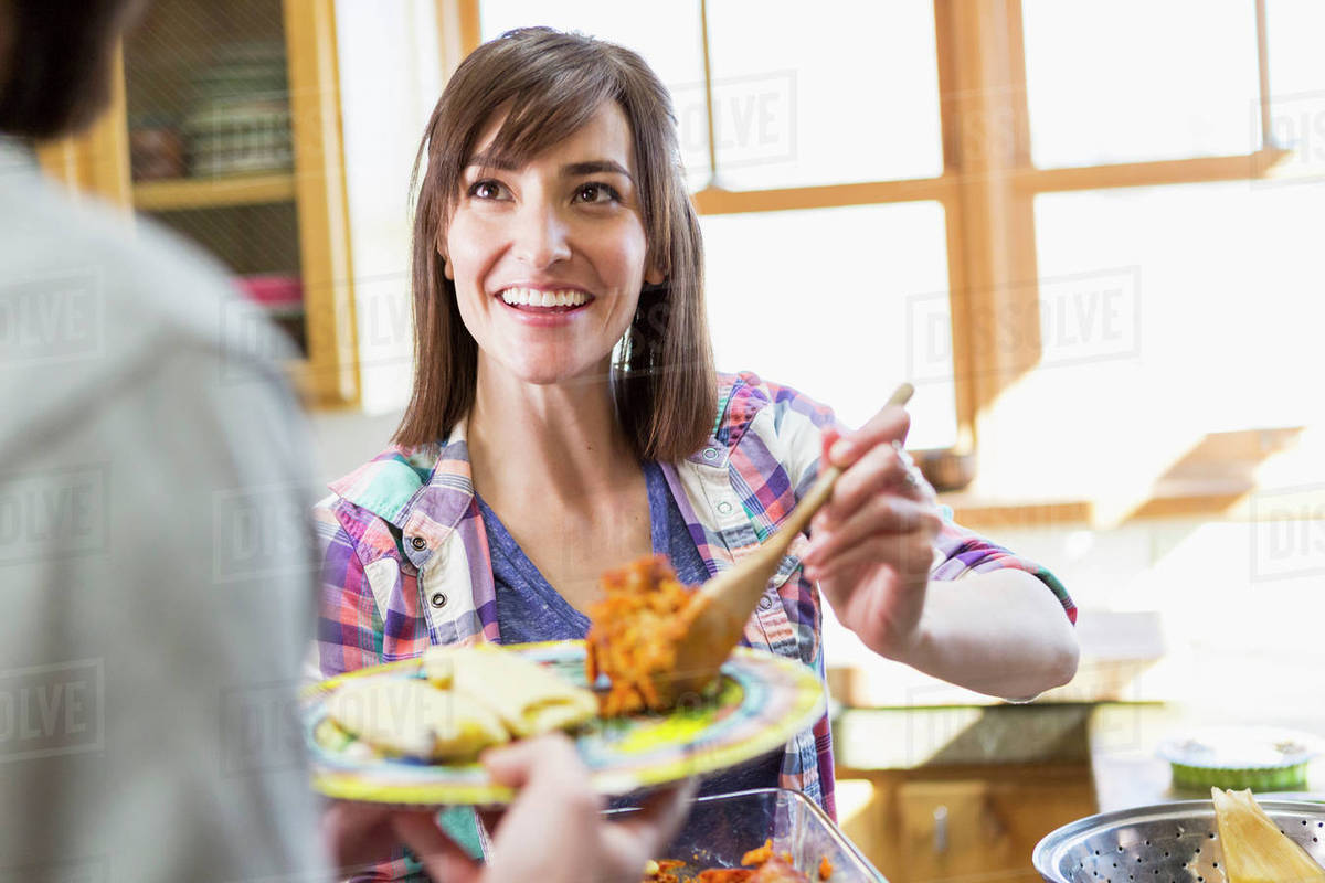 Hispanic woman serving boyfriend in kitchen - Stock Photo - Dissolve