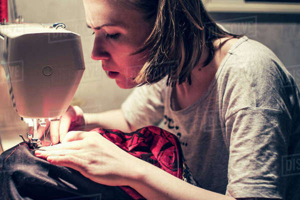Caucasian woman using sewing machine - Royalty-free Stock Photo | Dissolve