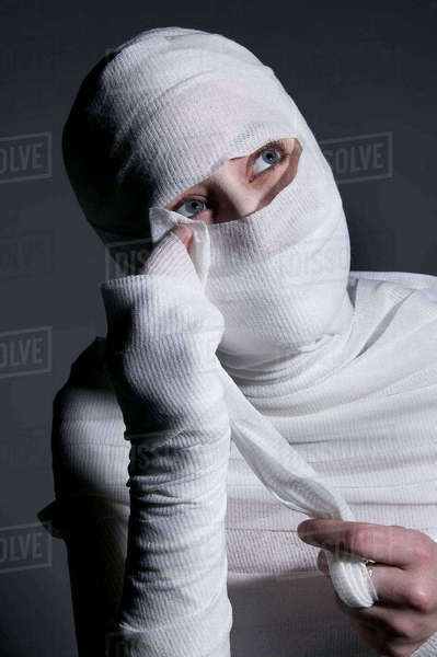 Woman unwrapping mummy costume - Stock Photo - Dissolve