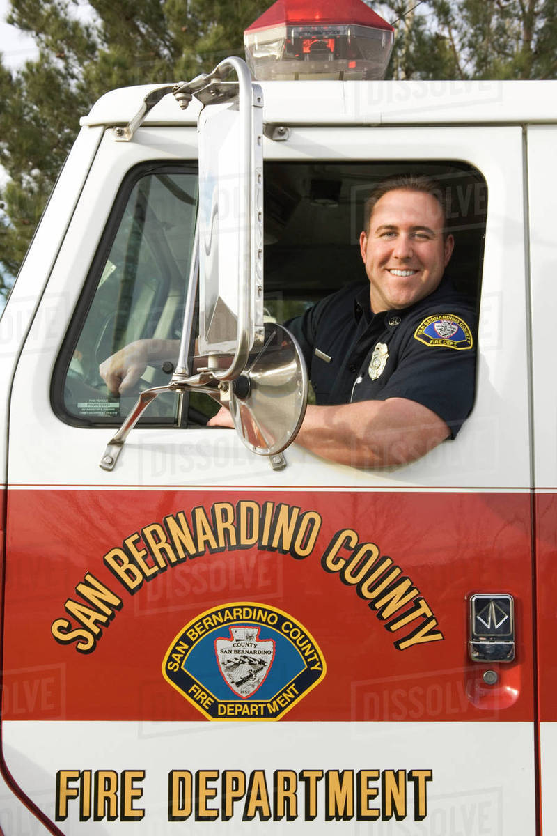 Caucasian firefighter smiling in fire truck - Royalty-free Stock Photo ...