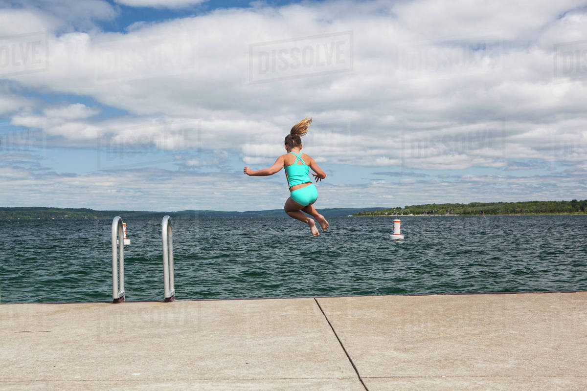 Caucasian girl jumping into lake - Royalty-free Stock Photo | Dissolve