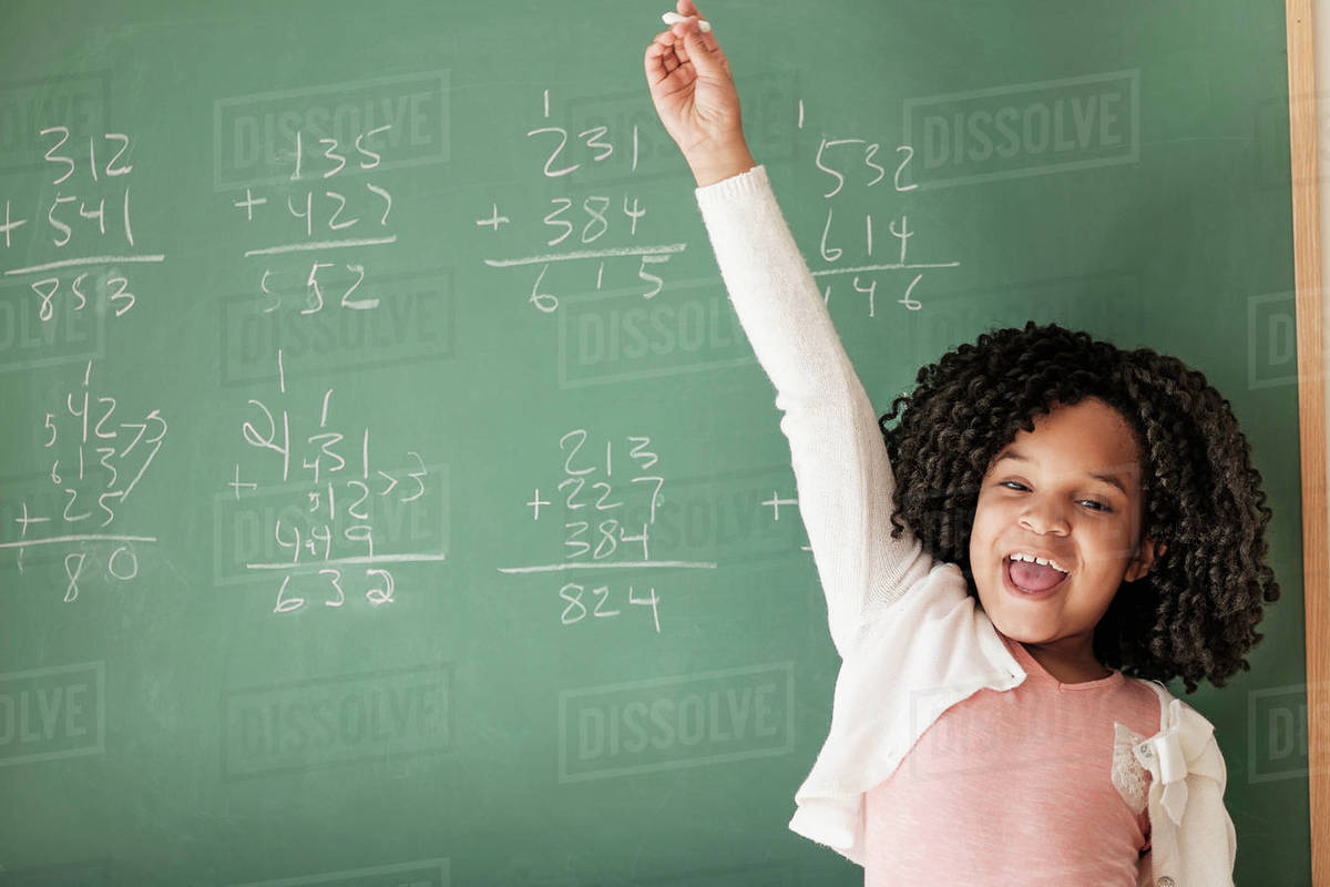 African American student cheering near chalkboard in classroom ...