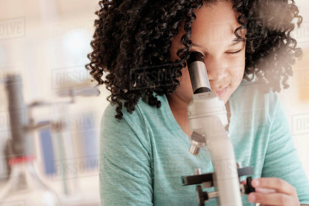 African American girl using microscope in science classroom - Royalty ...