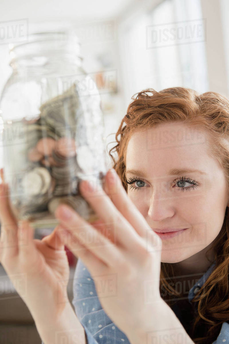 Caucasian woman looking at money in savings jar - Royalty-free Stock ...
