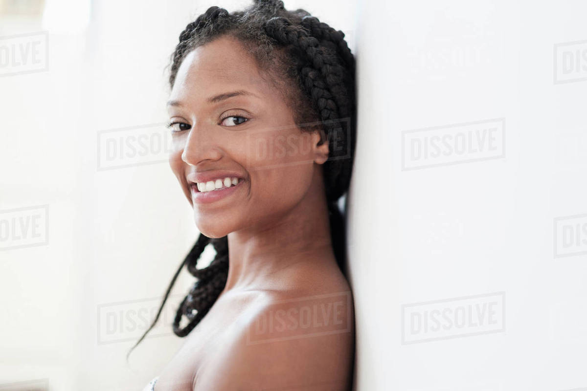 Smiling Black woman leaning on wall - Stock Photo - Dissolve