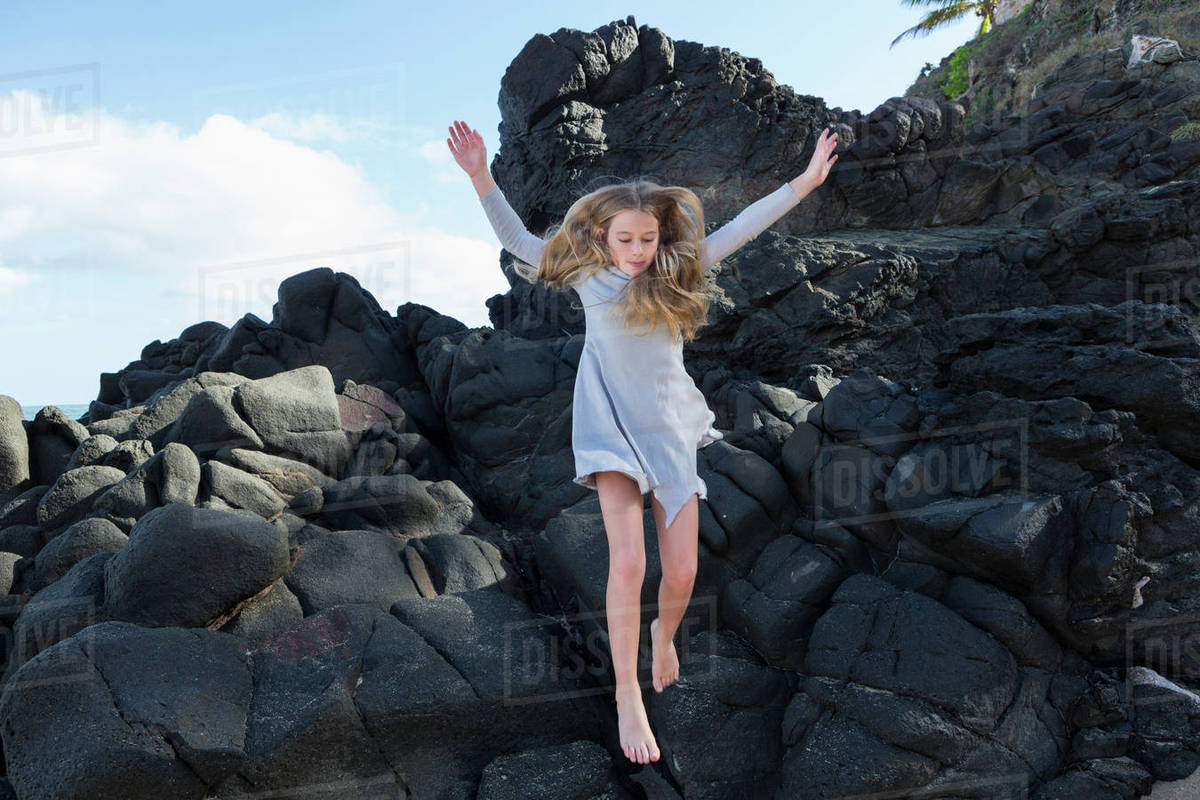 Caucasian girl jumping off rocks at beach - Royalty-free Stock Photo ...