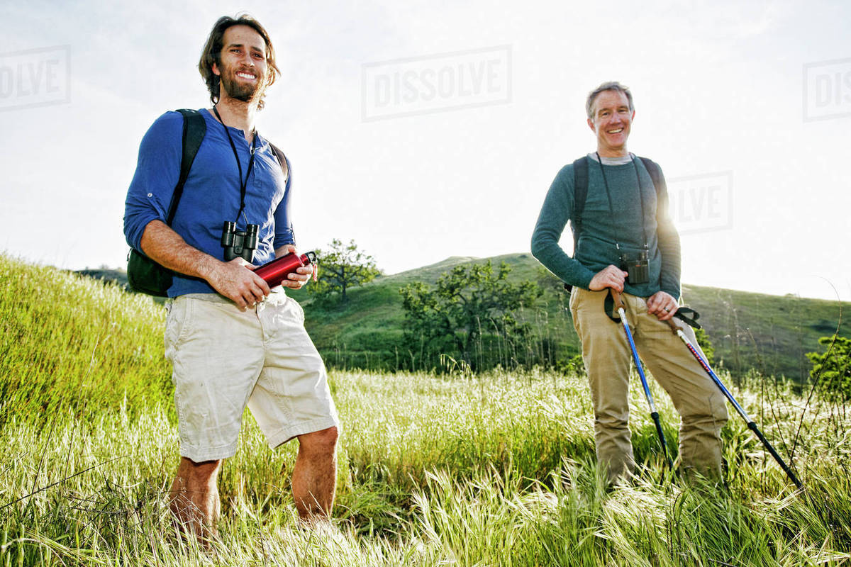 Caucasian hikers standing in grass on mountain - Stock Photo - Dissolve
