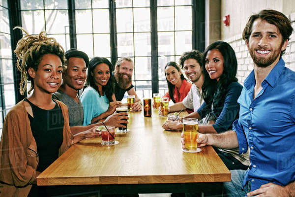 Smiling friends posing at table in bar - Royalty-free Stock Photo ...