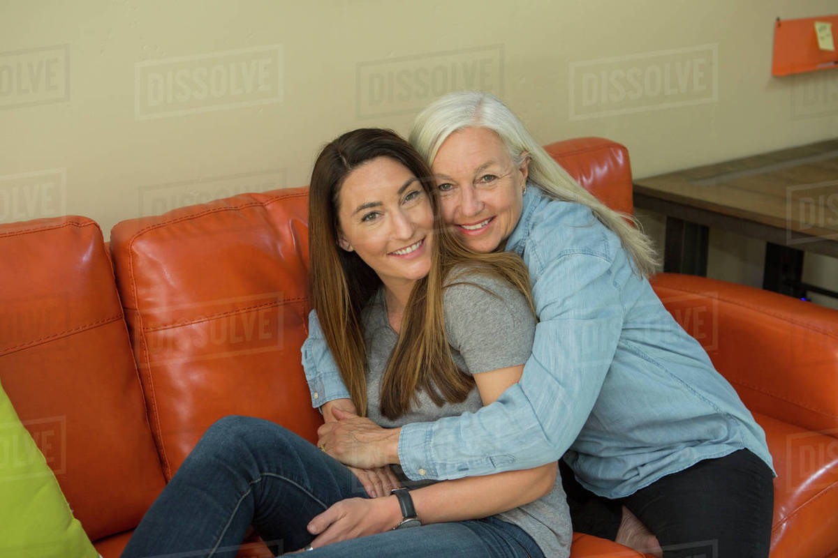 Caucasian women hugging on sofa - Royalty-free Stock Photo | Dissolve