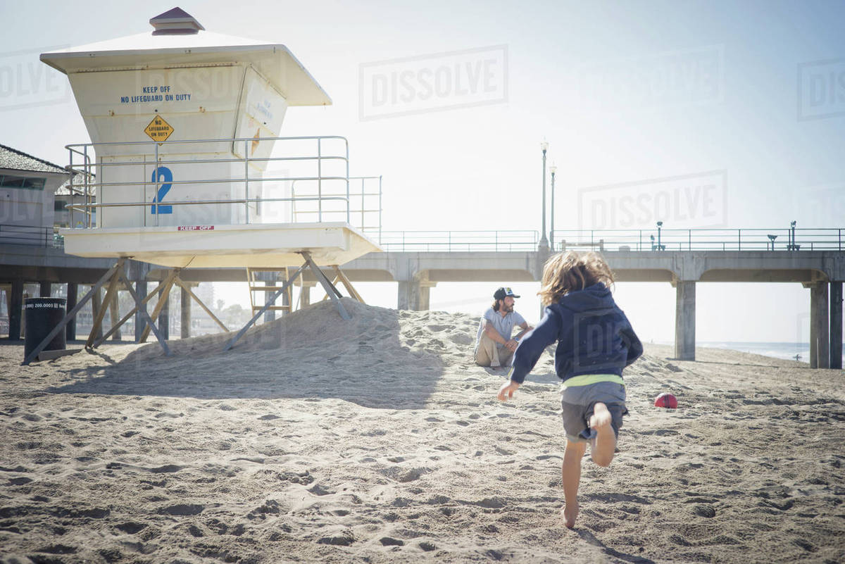Caucasian boy running to father on beach - Stock Photo - Dissolve