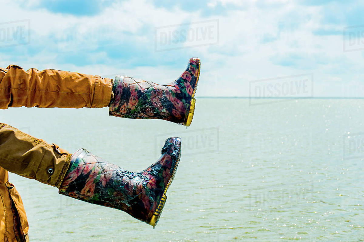 Person wearing boots on hands over water - Royalty-free Stock Photo ...