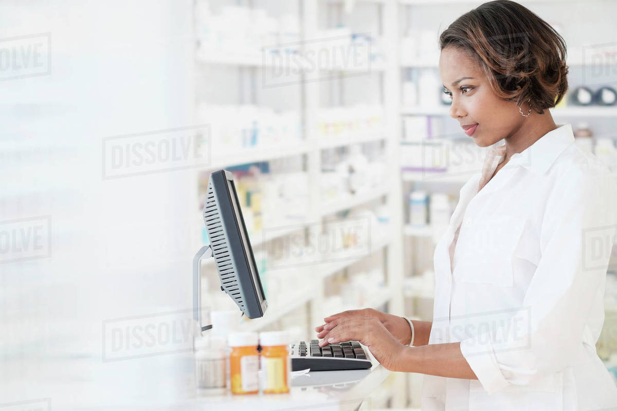 Smiling Black pharmacist using computer - Stock Photo - Dissolve