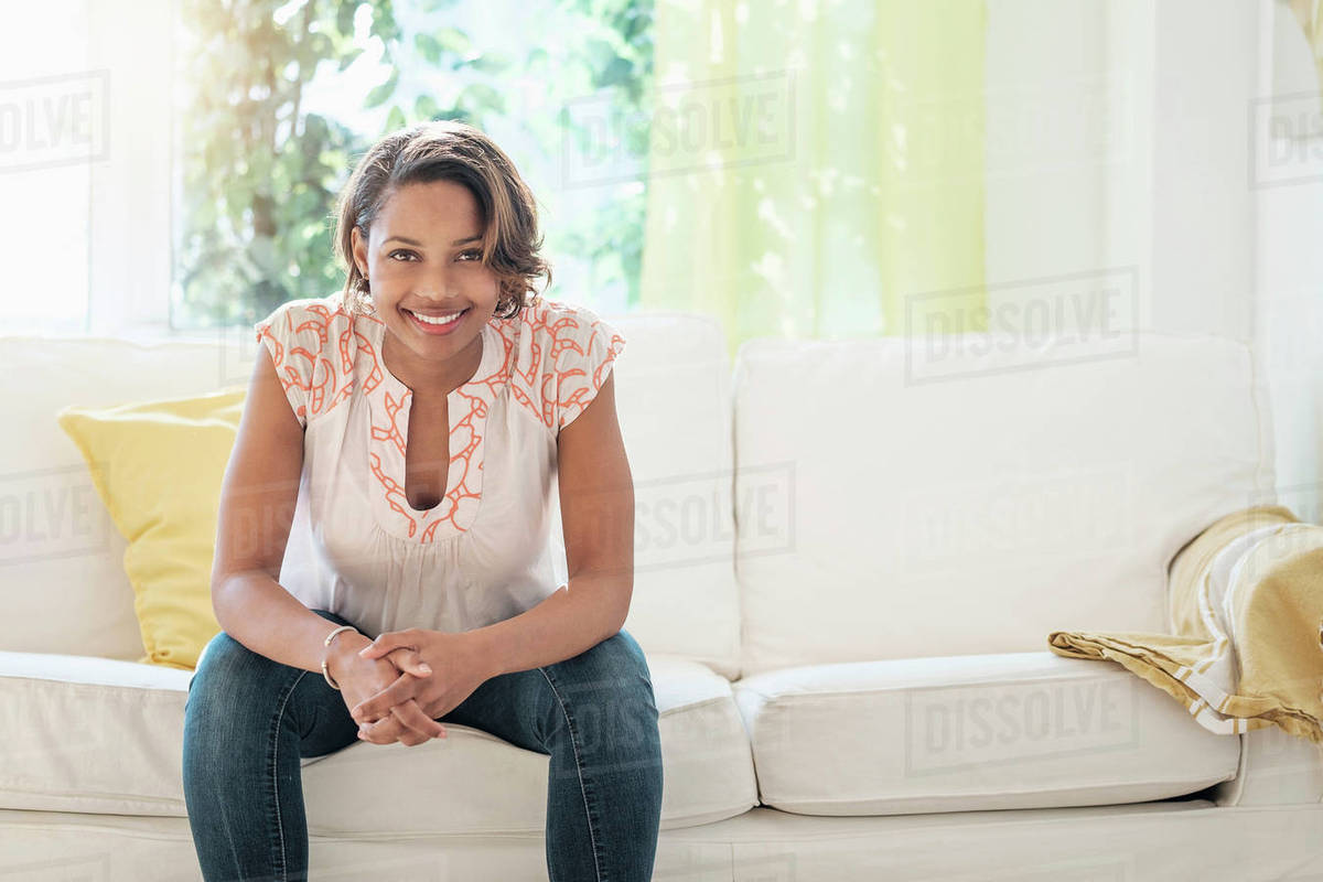 Black woman smiling on sofa - Stock Photo - Dissolve