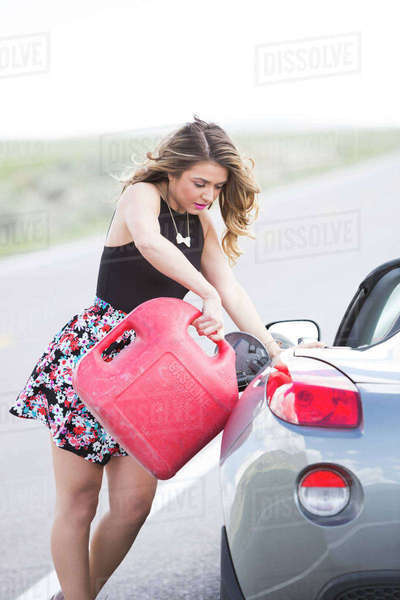Caucasian woman pouring fuel from gas can into sports car - Royalty ...