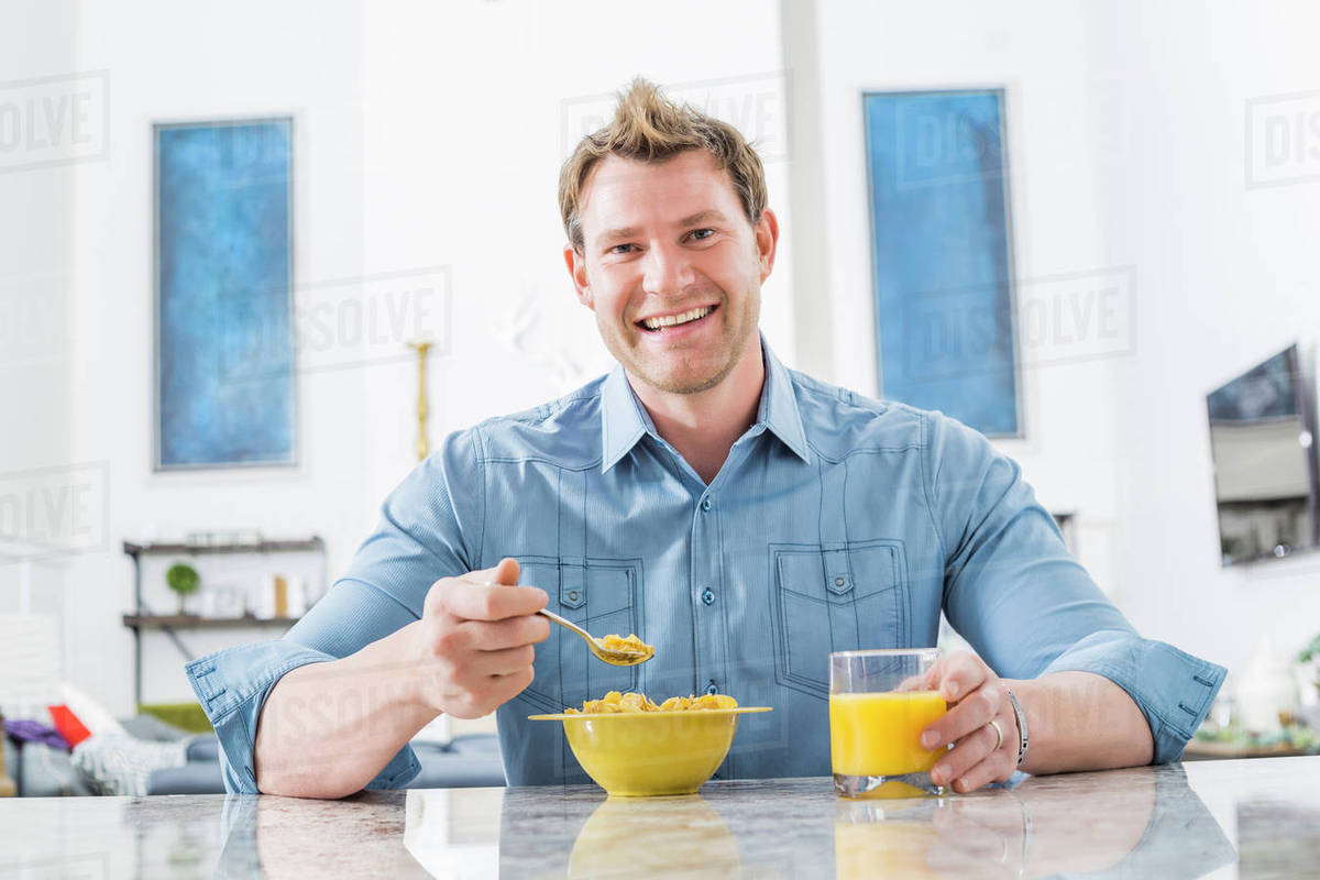 Caucasian man eating cereal in kitchen - Royalty-free Stock Photo ...