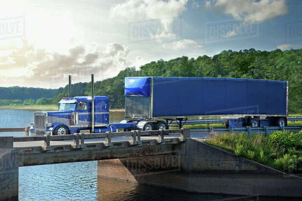 Semi-truck driving on bridge over river - Stock Photo - Dissolve