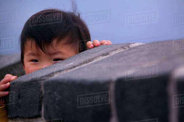 Eyes of boy peeking over stone wall - Royalty-free Stock Photo | Dissolve