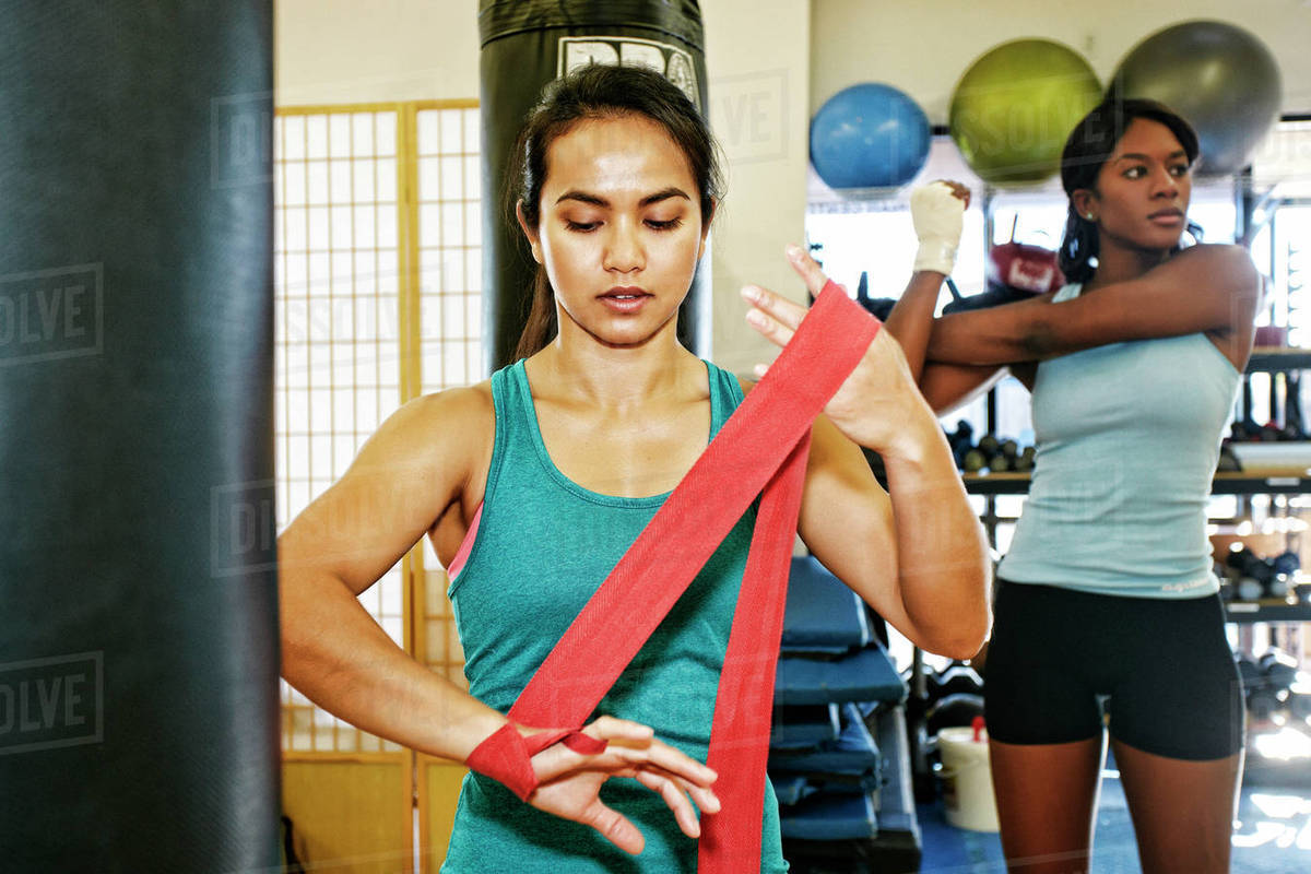 Woman wrapping hand in gymnasium - Stock Photo - Dissolve